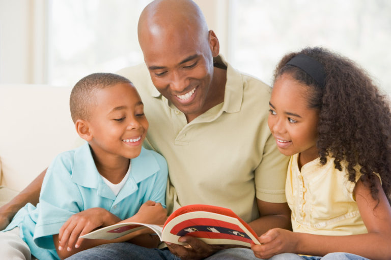 man-and-two-children-sitting-in-living-room-reading-book-and-smiling ...